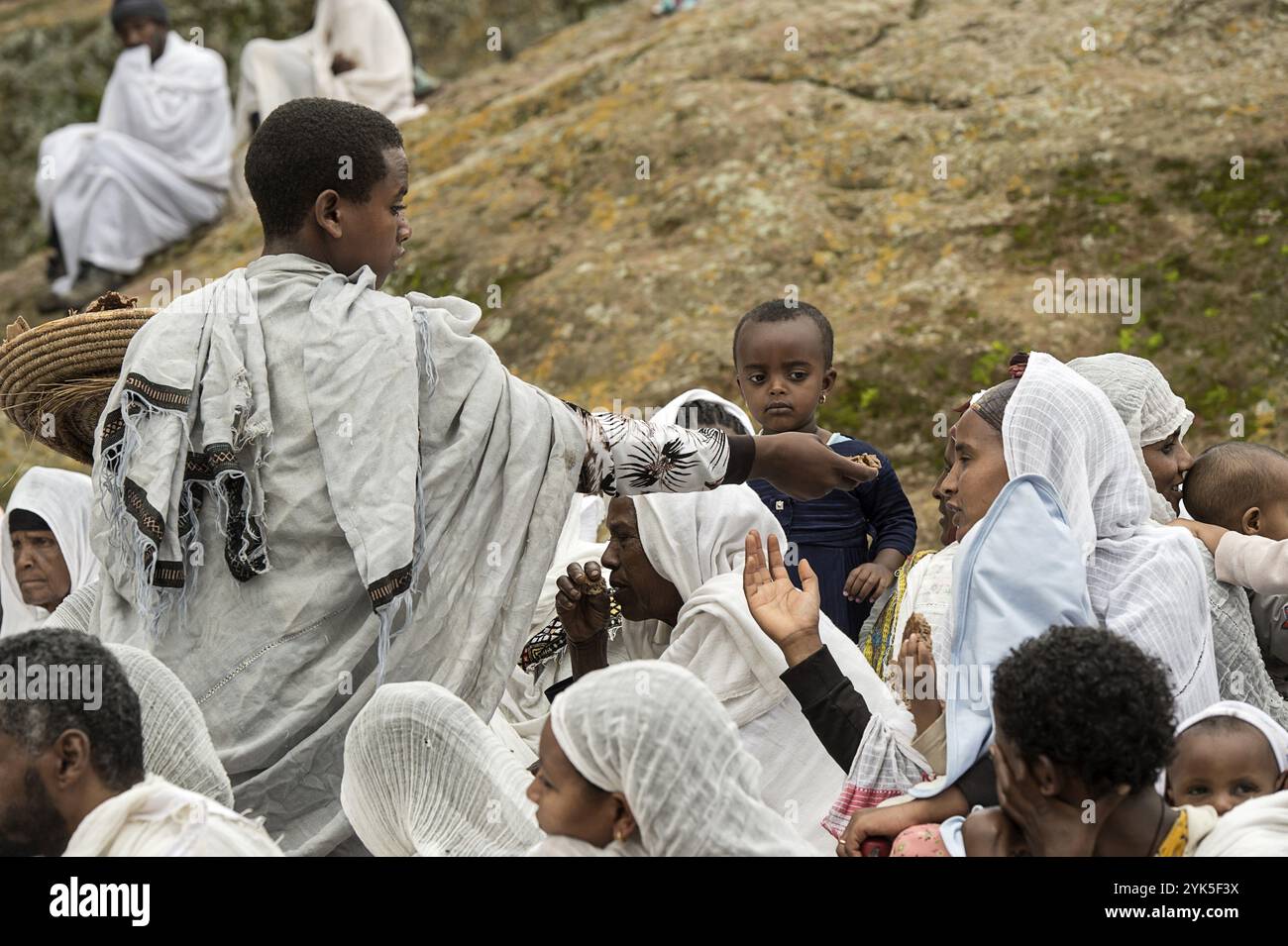 Altar boy distributes blessed bread to worshippers in traditional white ...