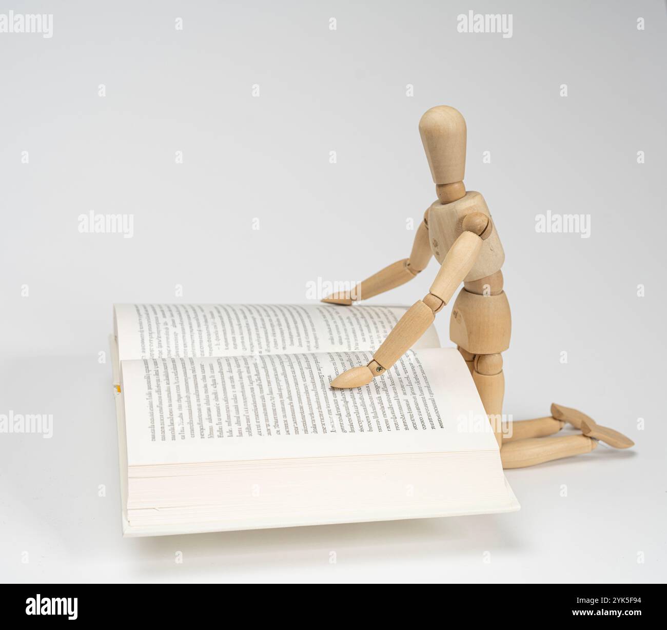 a wooden dummy reading a book on a white background Stock Photo - Alamy