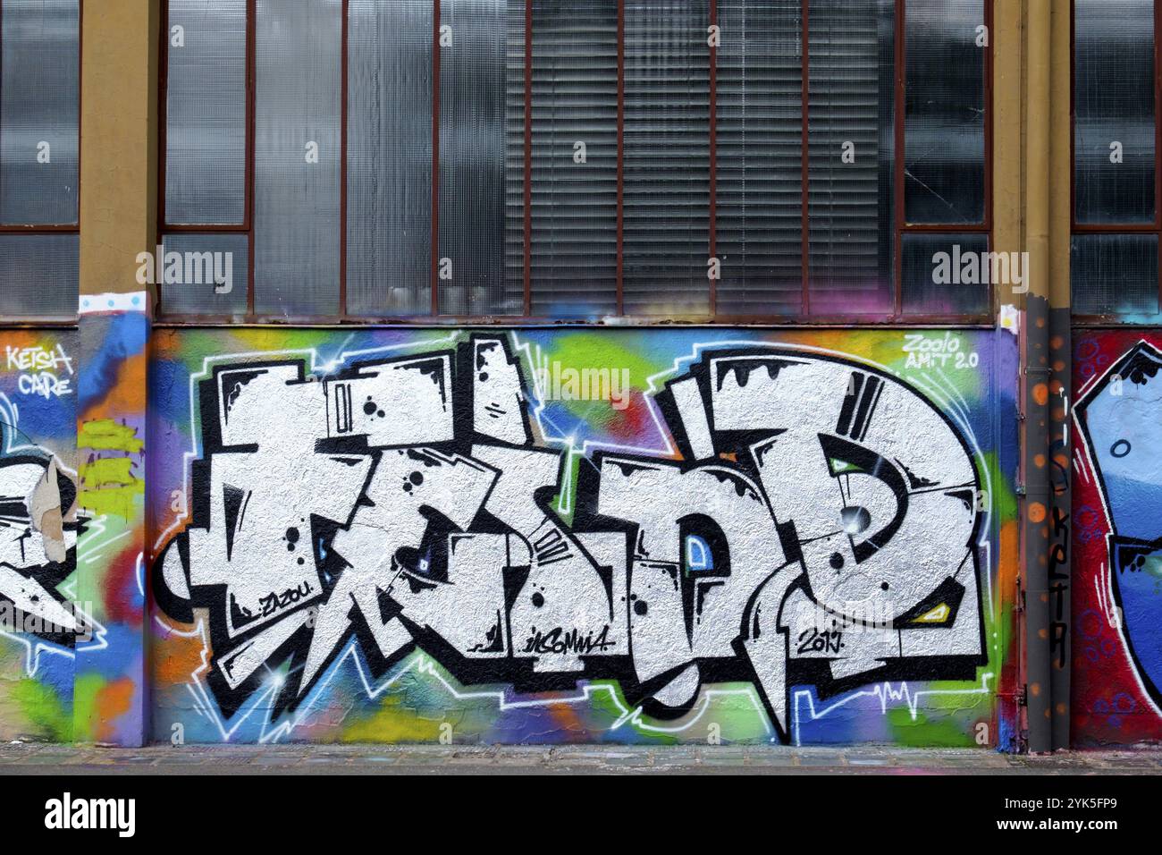 Large-scale graffiti with white letters and a colourful background on a ...