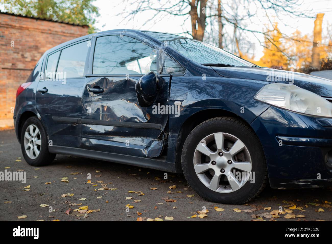Damaged blue car with dents and scratches on the side, showing the ...