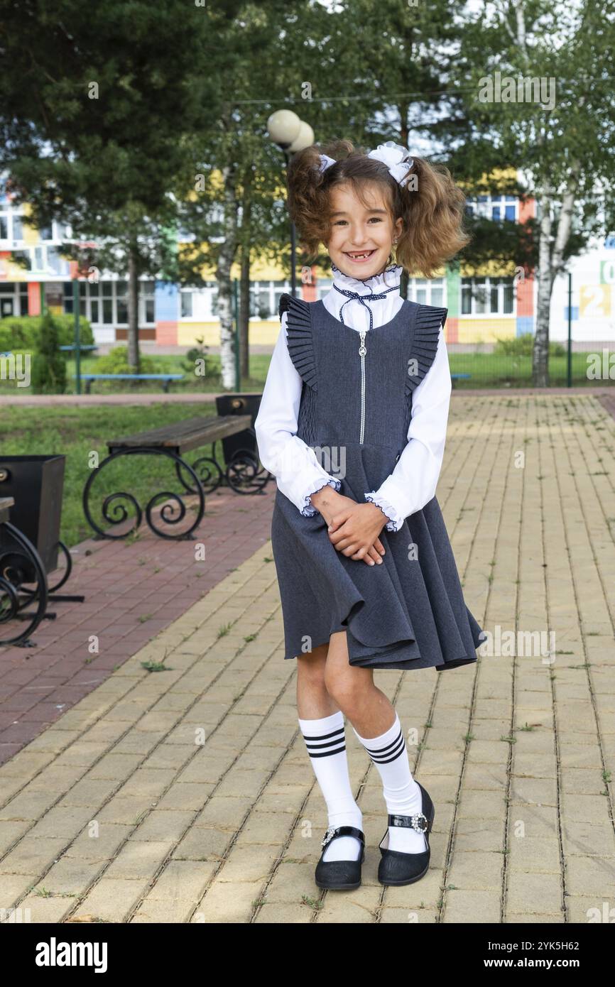 Cheerful funny girl with a toothless smile in a school uniform with ...