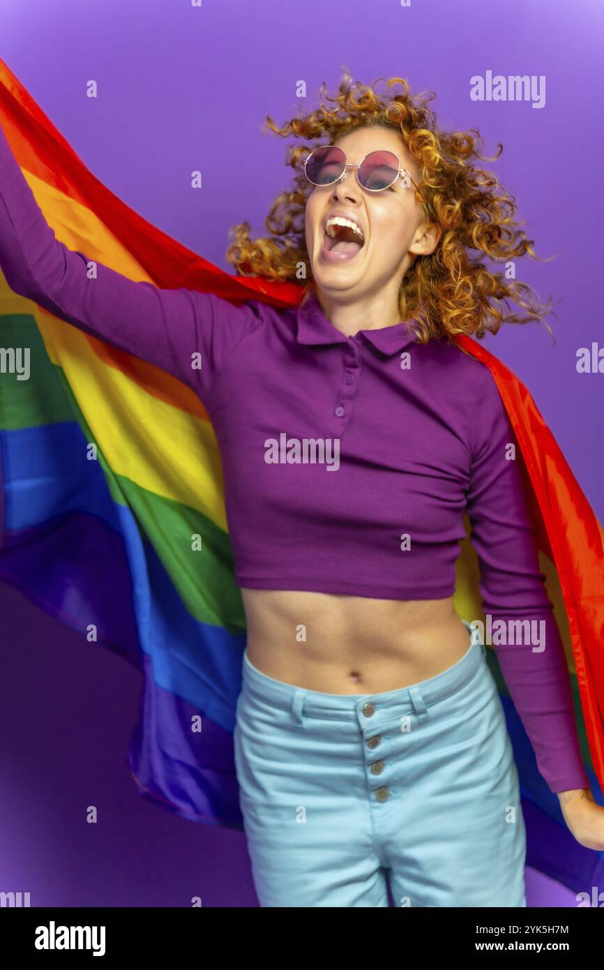 Studio portrait with purple background of a happy woman jumping holding ...