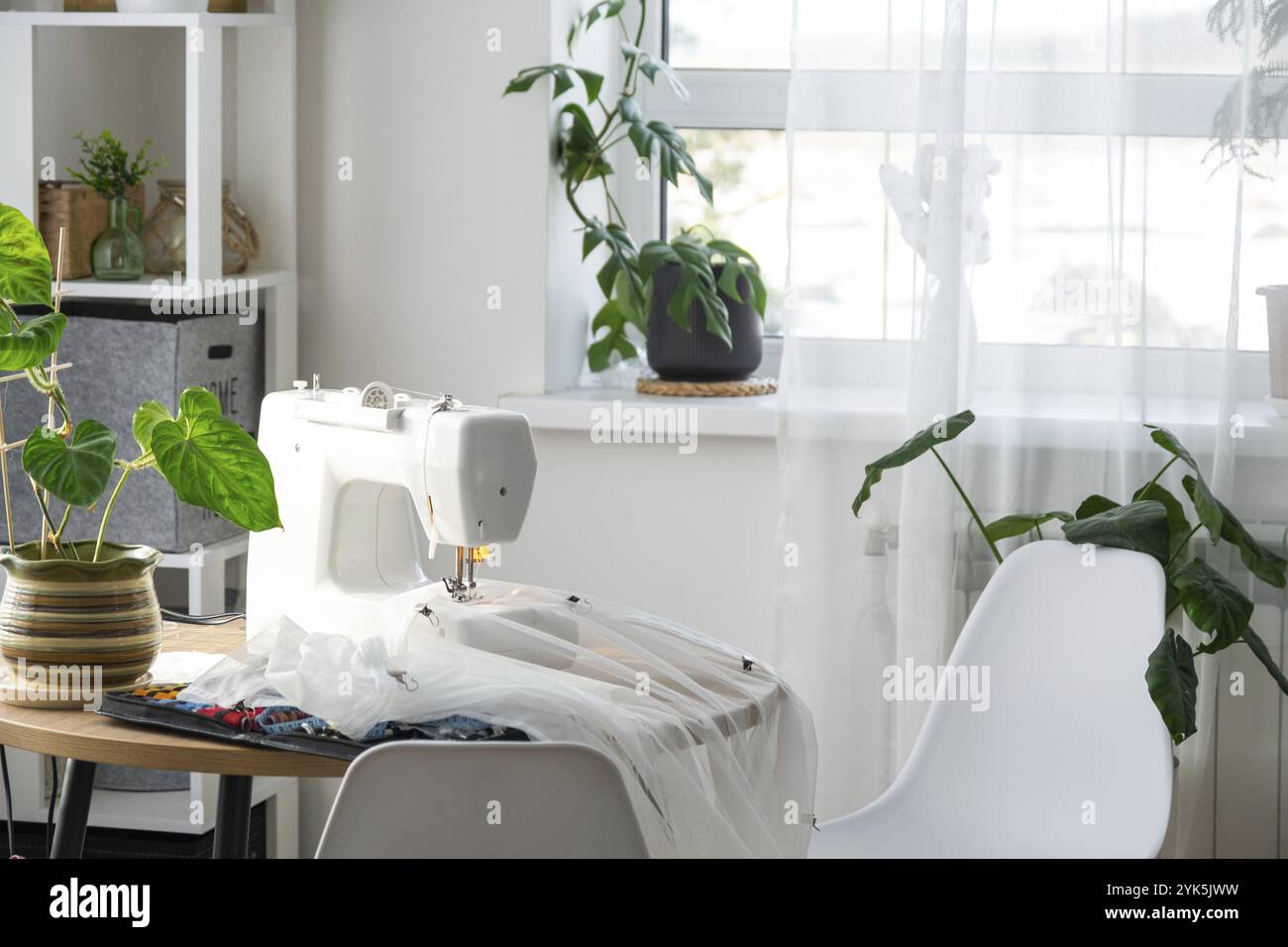 Sewing machine on a round table in the white interior of the house near ...