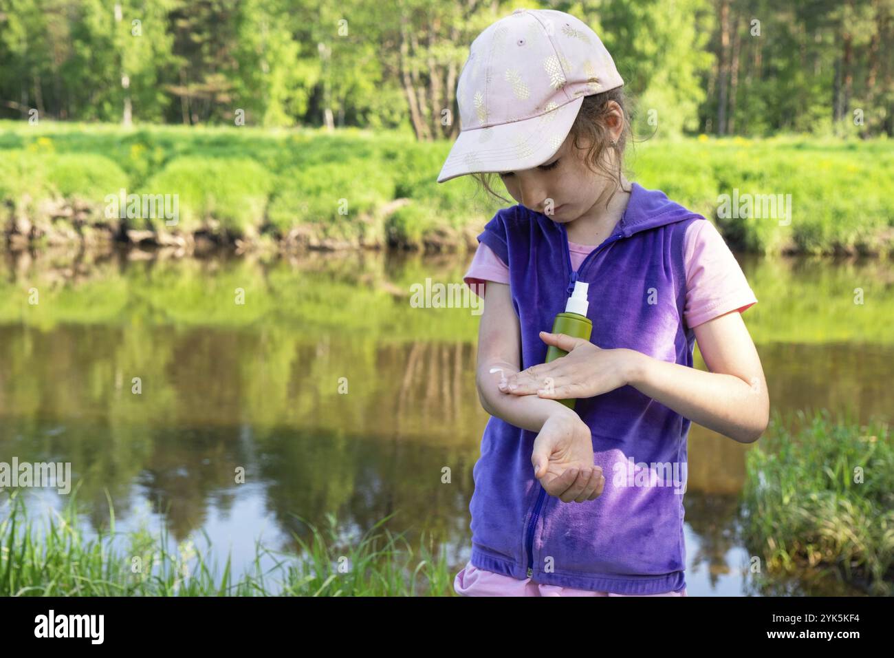 Girl sprays mosquito spray on the skin in nature that bite her hands ...