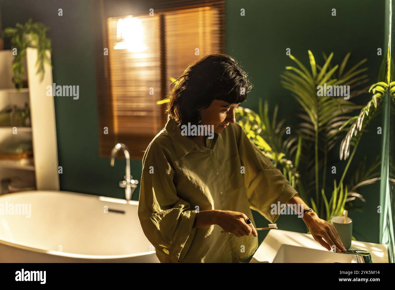 Non binary woman washing the teeth at home in the bathroom Stock Photo ...