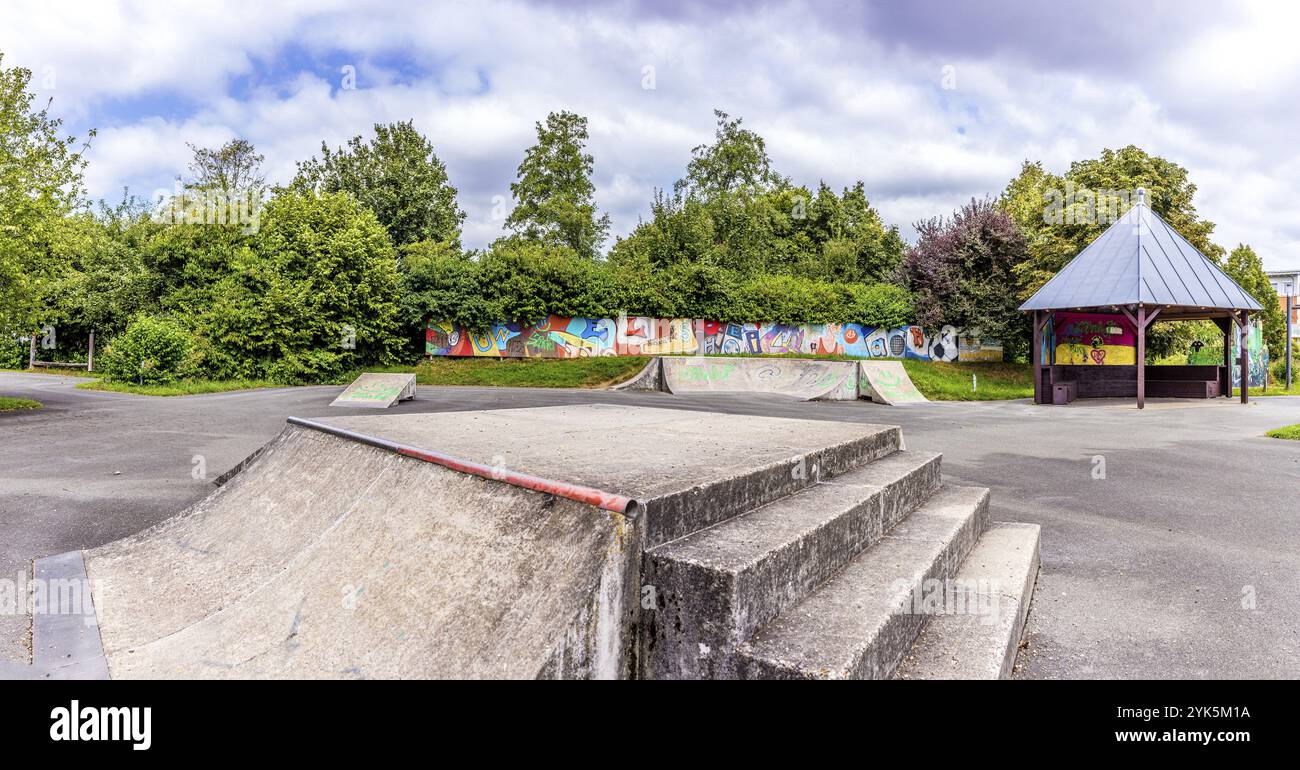 A skate park with concrete ramps and graffiti walls, surrounded by ...