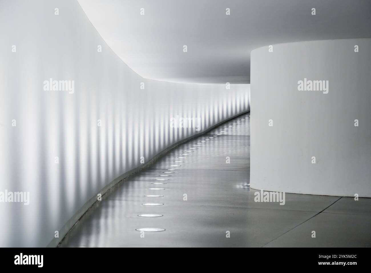 A minimalist, futuristic hallway with white walls and a curved design ...
