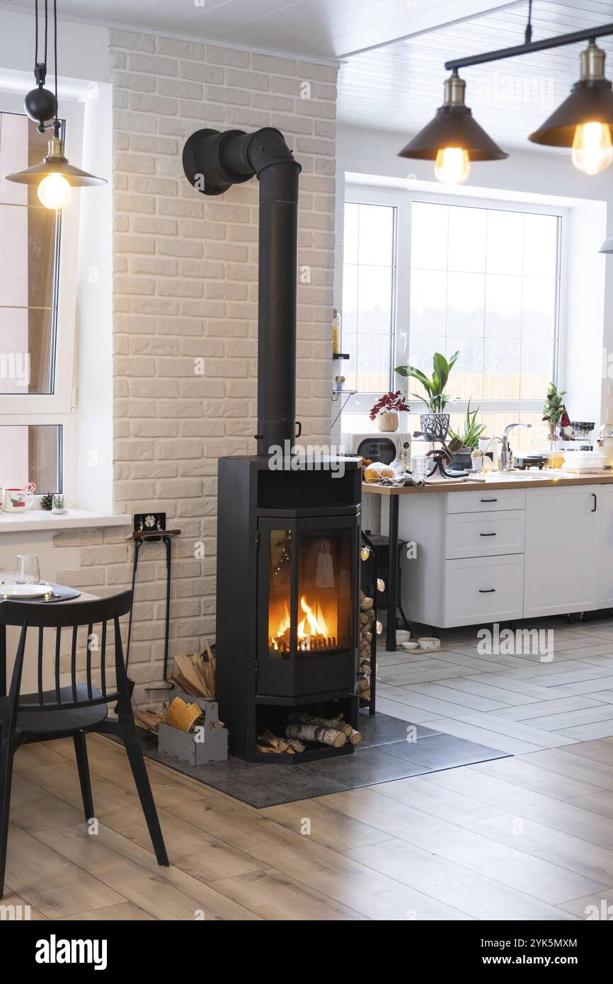 Festive interior of house is decorated for Christmas and New Year in loft style with black stove ...
