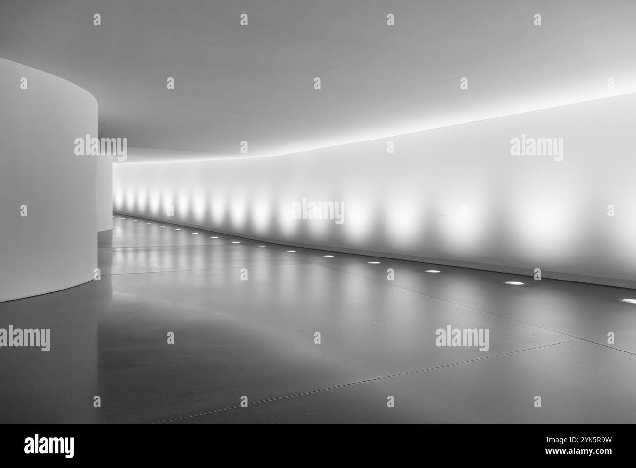 A minimalist, futuristic hallway with white walls and a curved design ...