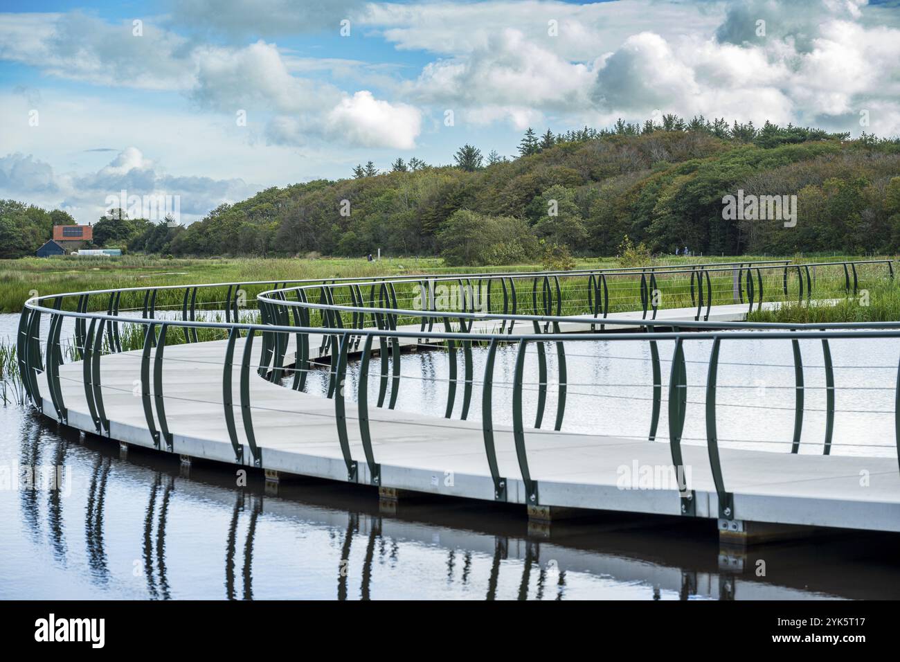 A modern bridge winds its way across the water against a backdrop of ...