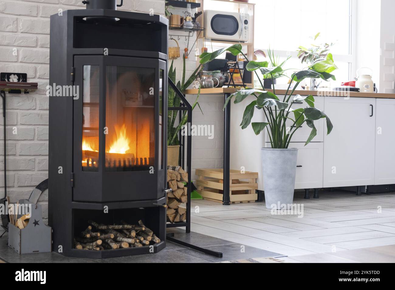 Black Metal Steel fireplace stove with fire and firewood near kitchen ...