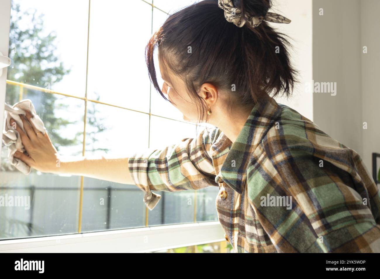 Woman manually washes the window of the house with a rag with spray ...