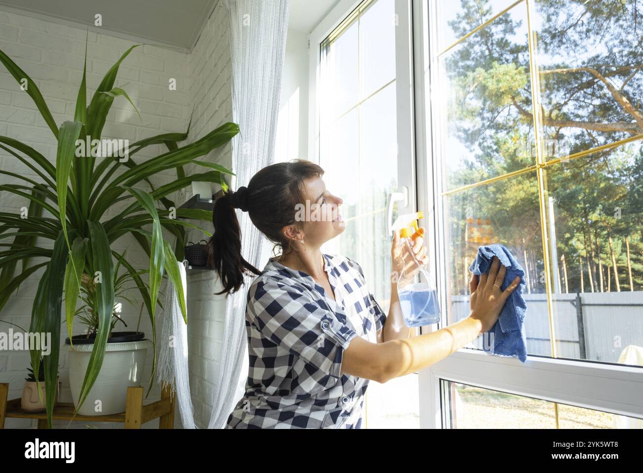 Woman manually washes the window of the house with a rag with spray ...