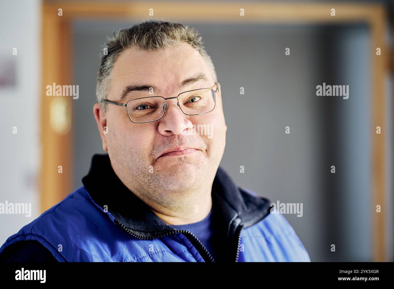 Man tries to hold back smile, face of an obese male with glasses is ...