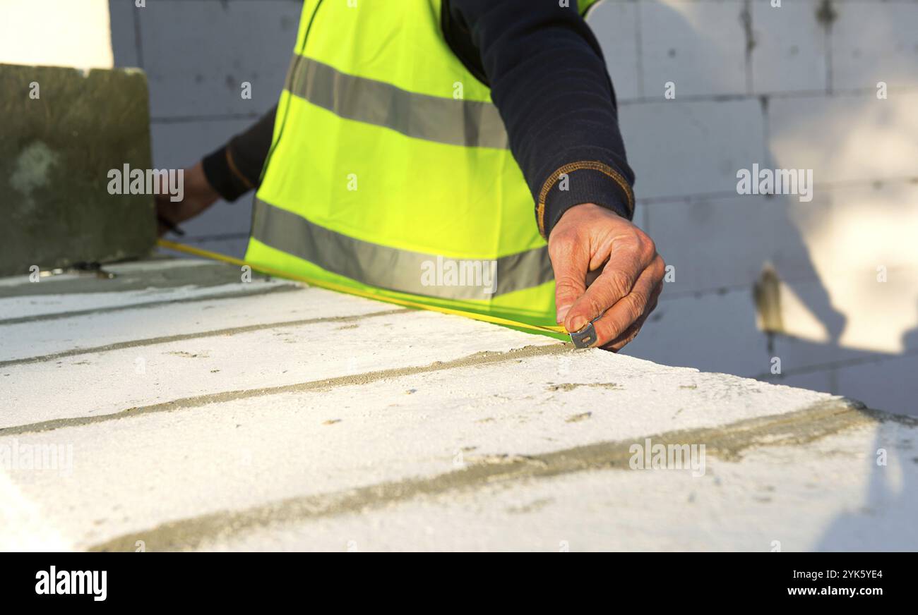 Construction worker at construction site measures the length of the ...