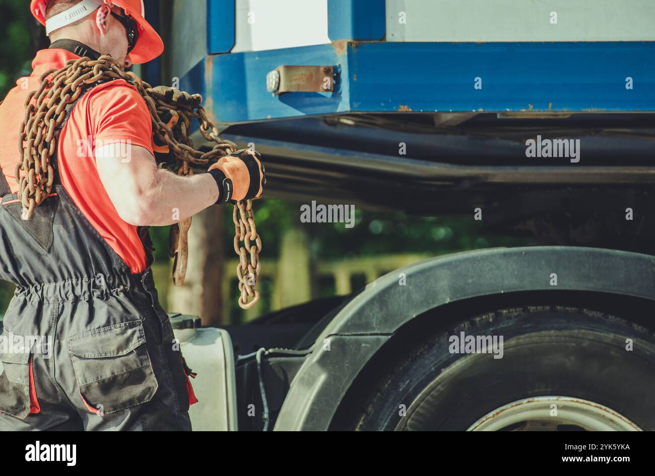 A worker in protective gear fastens a large cargo container to a ...