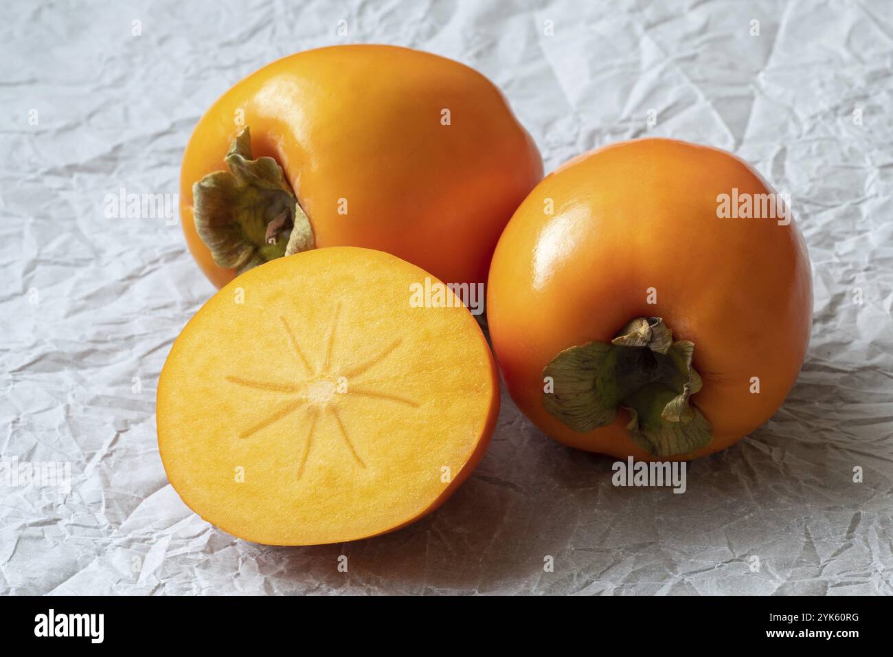 Whole and half of fresh ripe persimmons. Japanese persimmon (Diospyros ...