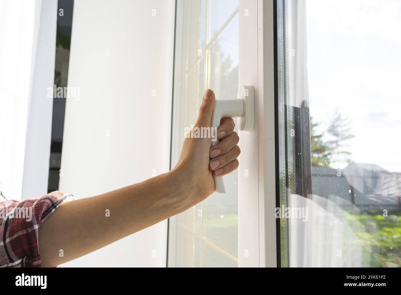 The hand holds the handle of a plastic double-glazed window, closing ...