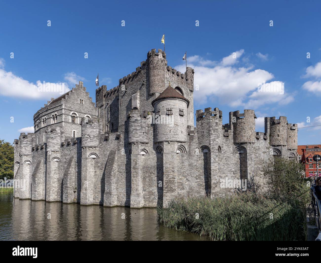 Stone walls of medieval Gravensteen Castle and moat with blue sky ...