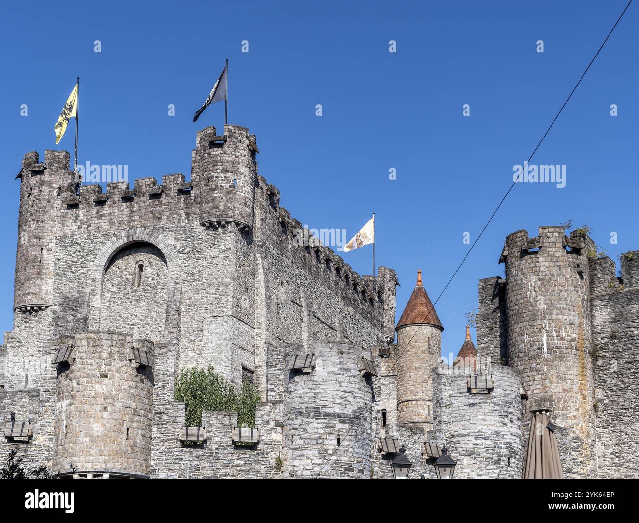 Stone walls of medieval Gravensteen Castle with flags and blue sky ...