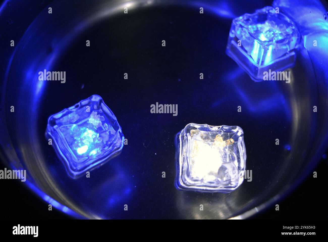 Beautiful and bright white, blue glowing ice cubes float in a glass ...