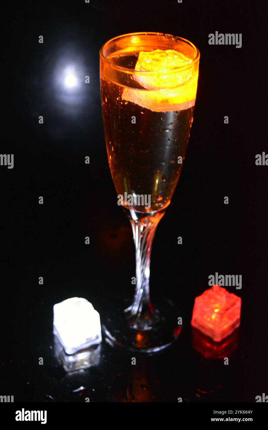 Beautiful and bright yellow glowing ice cube floats in a glass ...