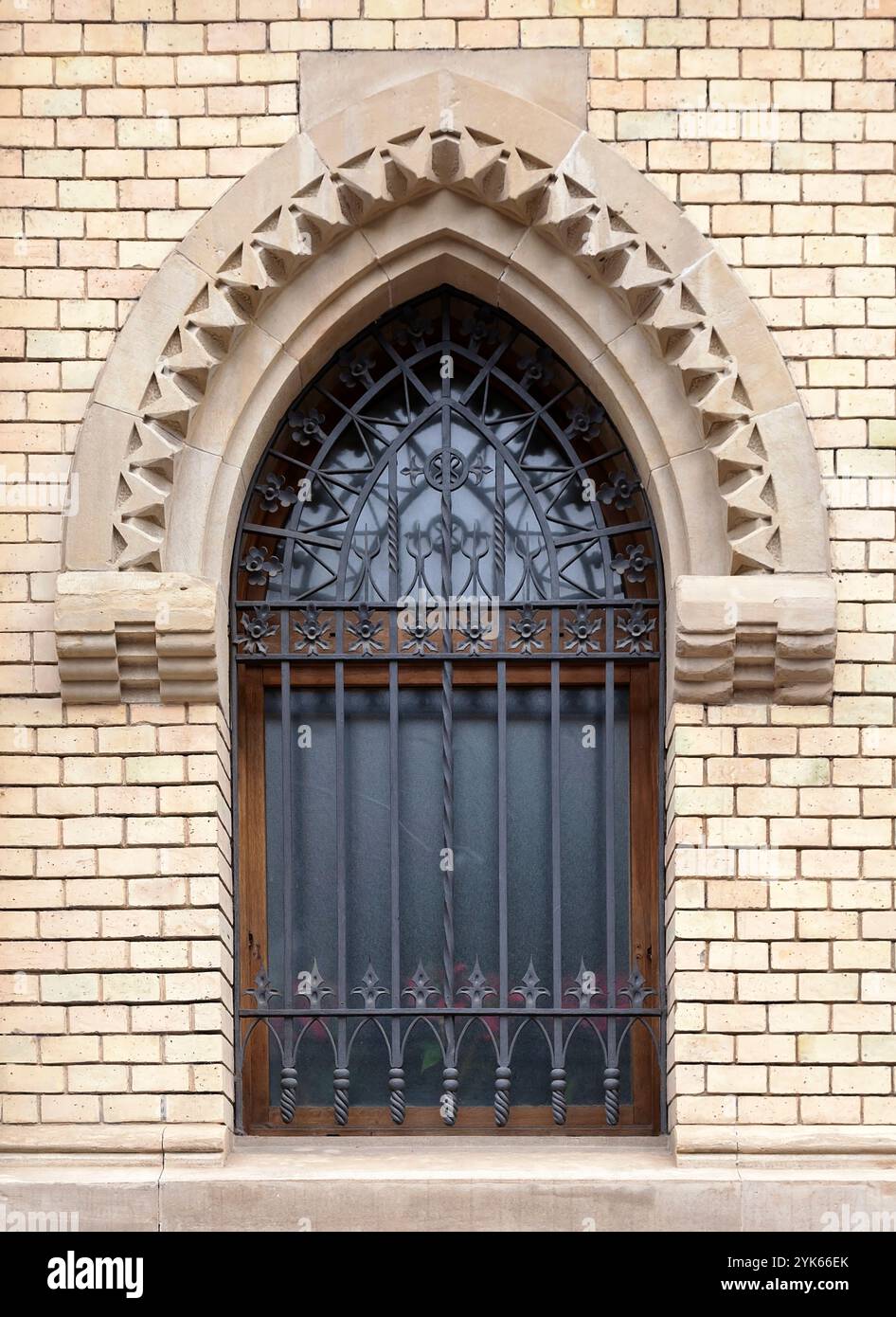 A detailed stone window featuring ornate carvings and a metal grid ...
