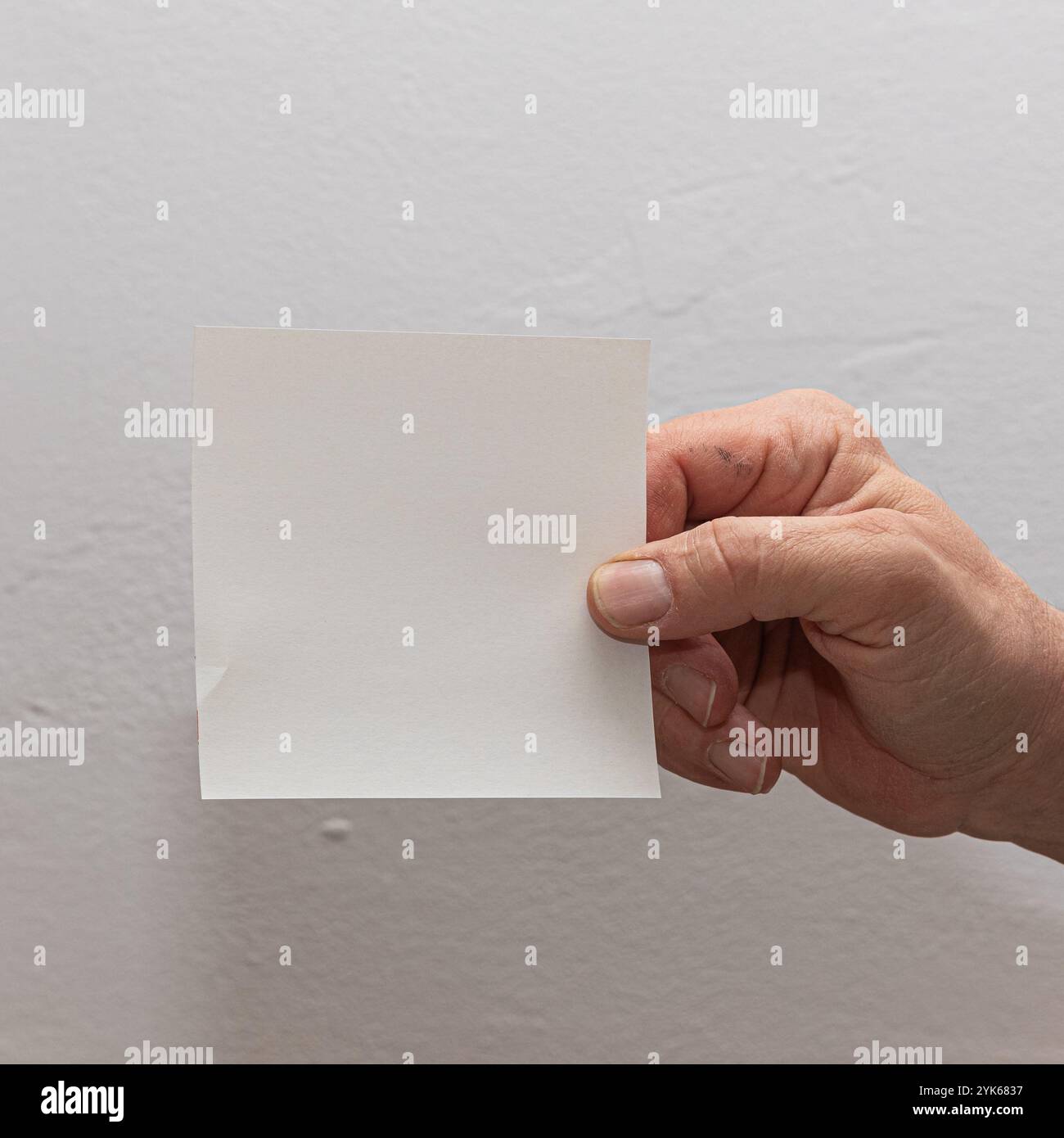 Hand holding a blank white paper on a plain background, ideal for ...
