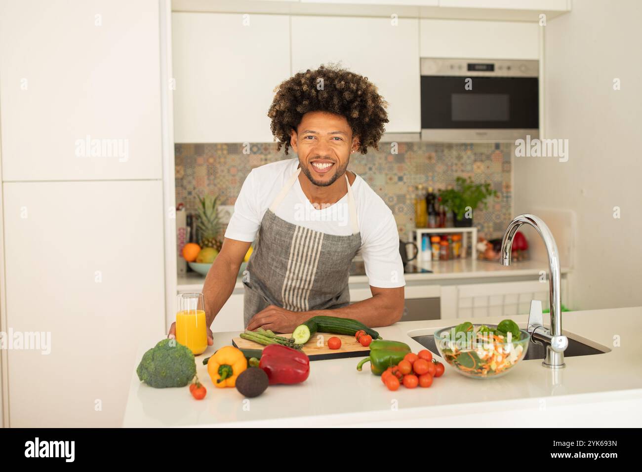 Preparing fresh vegetables in a modern kitchen with a joyful cook Stock ...