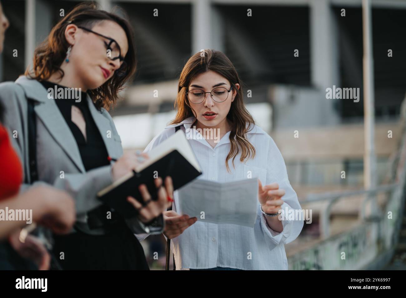 Businesswomen having an outdoor meeting discussing documents and taking ...