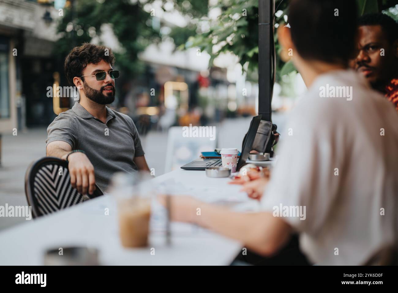 Outdoor business meeting at a cafe with diverse group of young ...