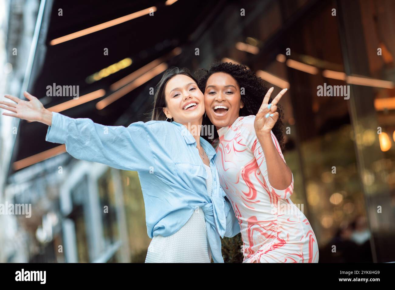 Two women celebrating joyfully outside a trendy cafe in the sunshine ...