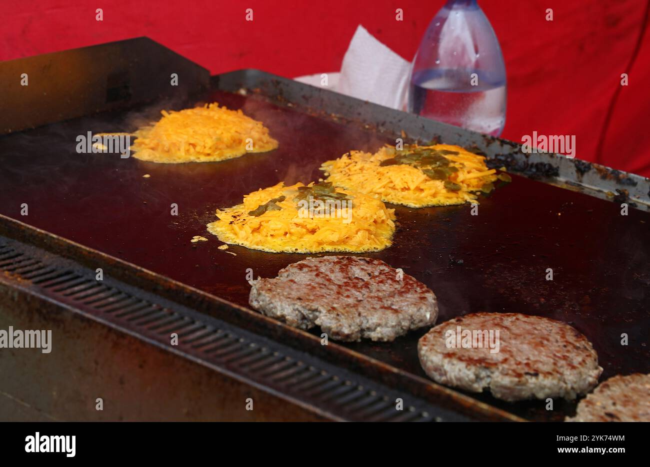 Ground beef patties and shredded cheese with jalapenos are sizzling on ...