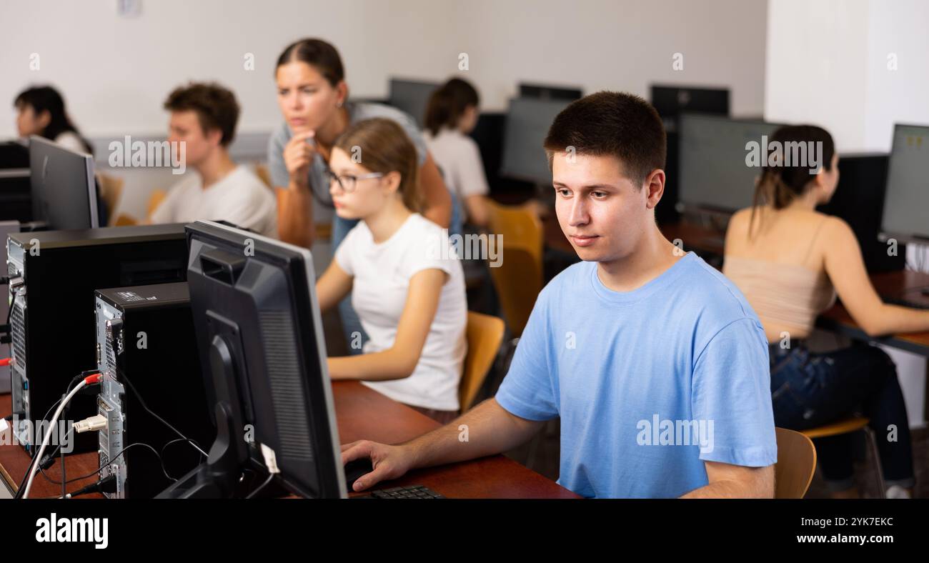 Smart male teen learning computer science while she is using a PC in ...