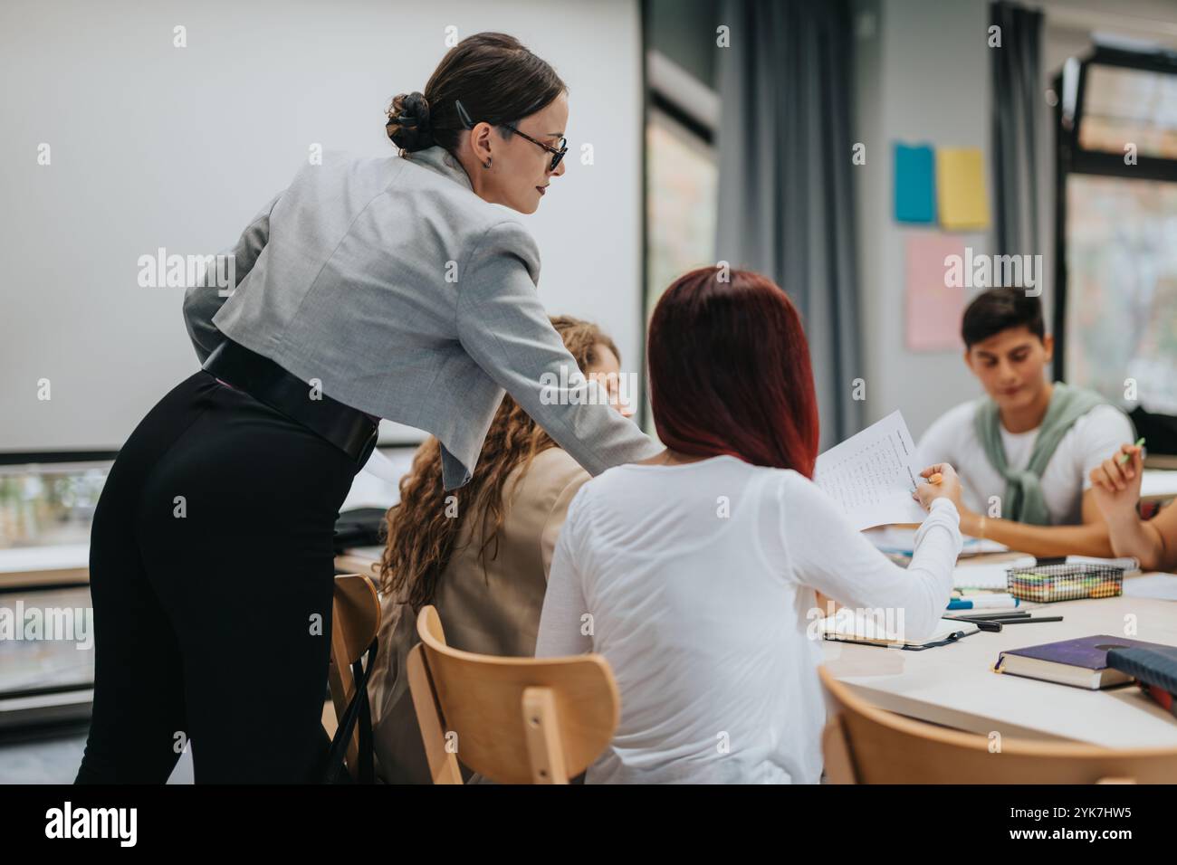 Teacher assisting students during collaborative class activity Stock ...