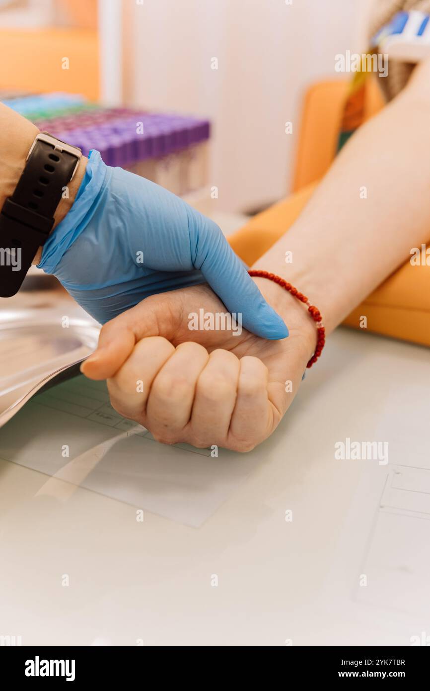 Medical professional holding patient's wrist during blood collection ...