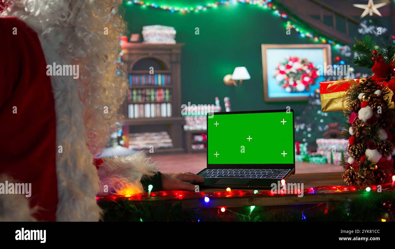 Santa Claus sitting next to copy space screen on device and reading ...