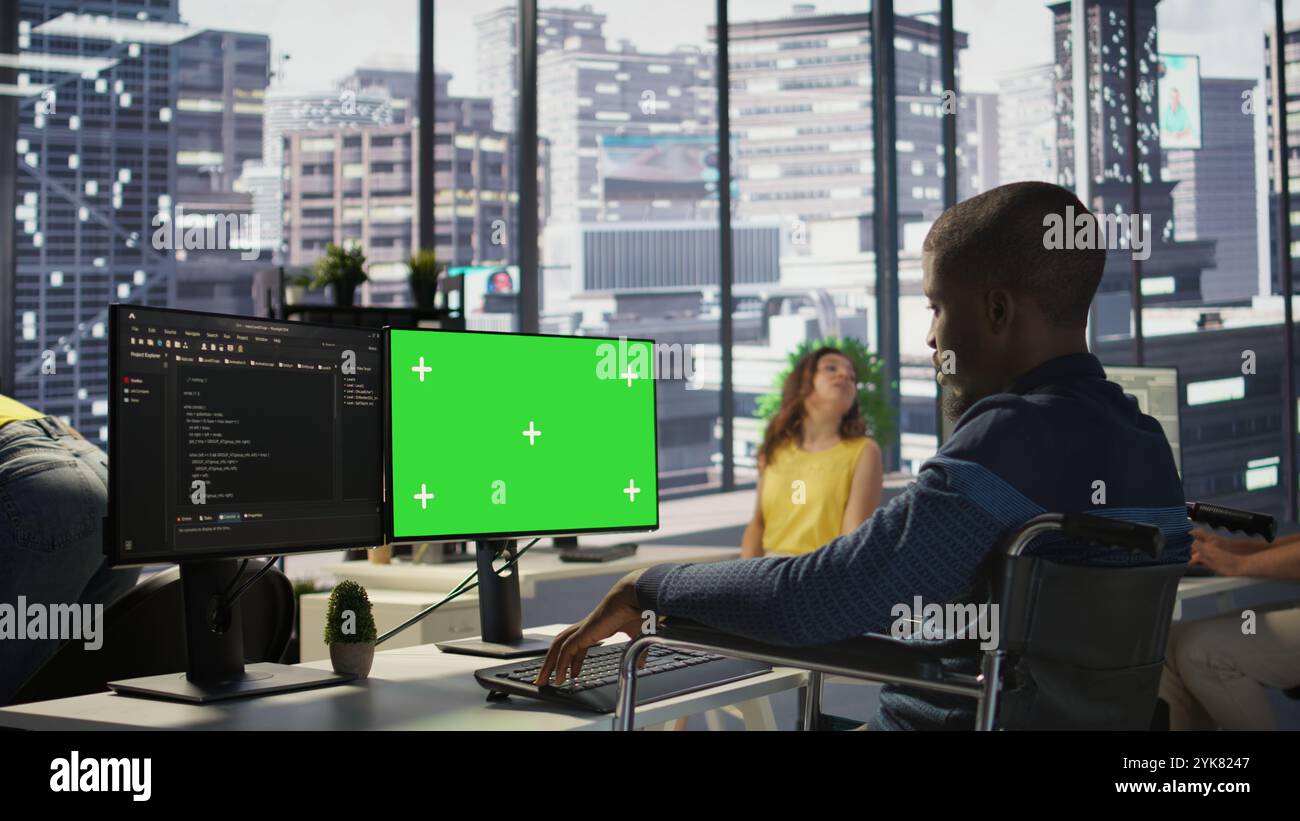 Developer with disability sitting in wheelchair fixing applications issues on green screen PC ...