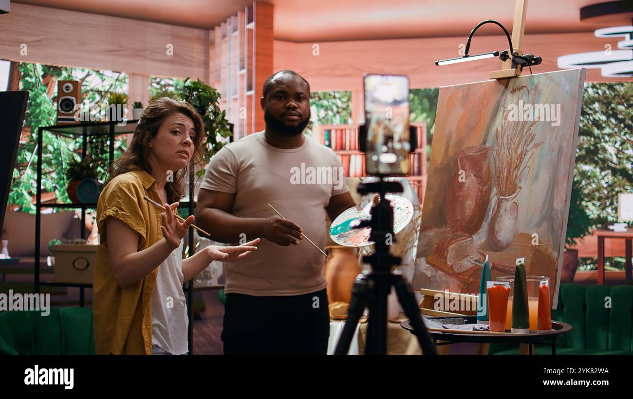 Woman painter filming her colleague during creative process and ...