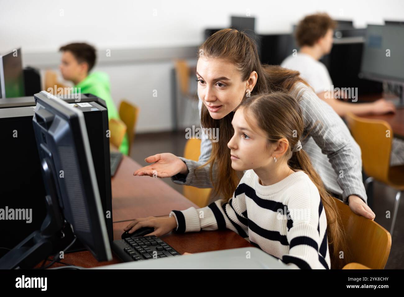 Female teacher and teenage girl looking at monitor of PC Stock Photo ...