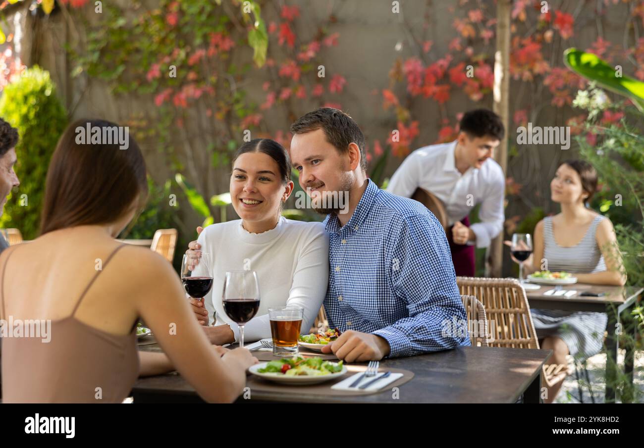 Meeting of two married couples in cozy open-air restaurant Stock Photo ...