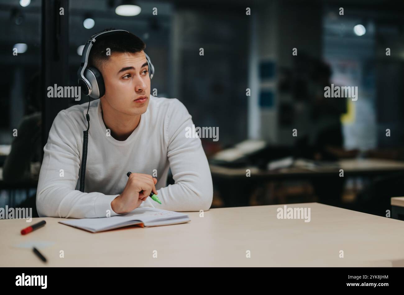 Focused student with headphones studying in a modern classroom Stock ...