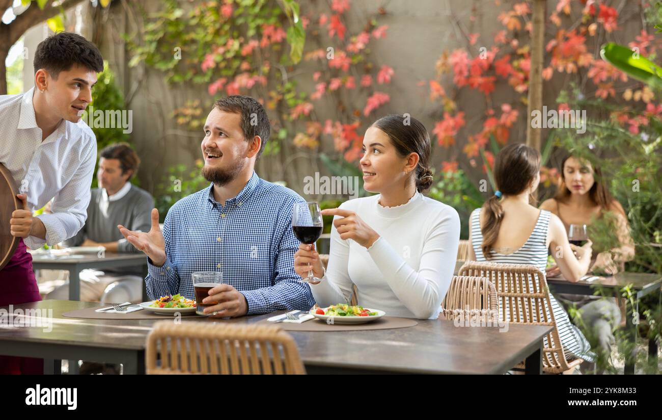 Waiter takes an order from a couple in love who decided to meet in an ...
