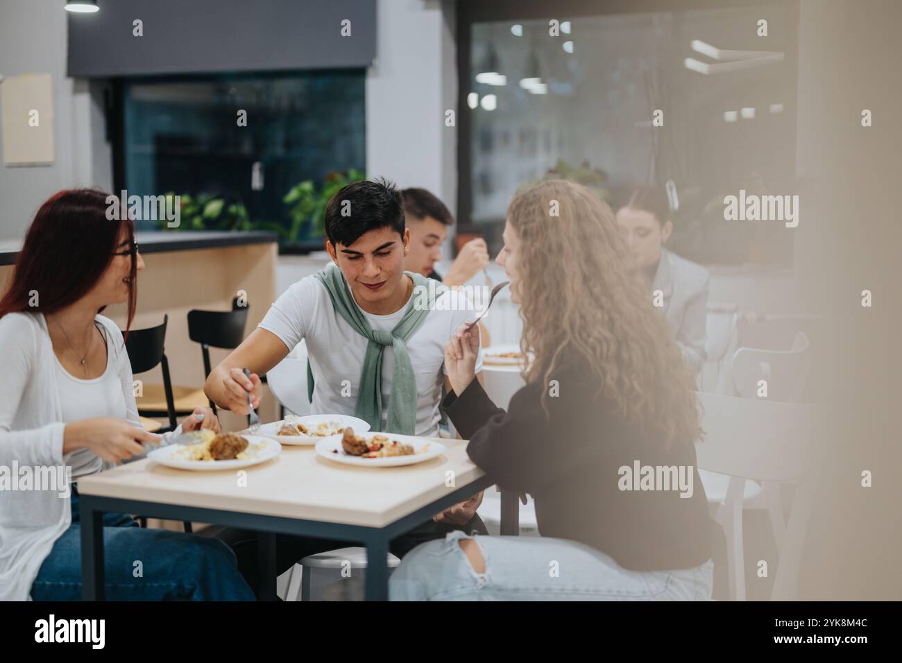 Students enjoying lunch together in a modern school cafeteria setting ...