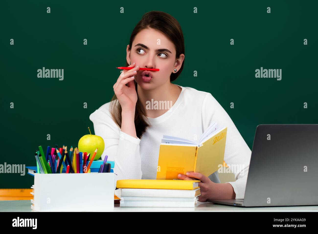 Portrait of funny funky crazy school girl with grimace pencil between ...