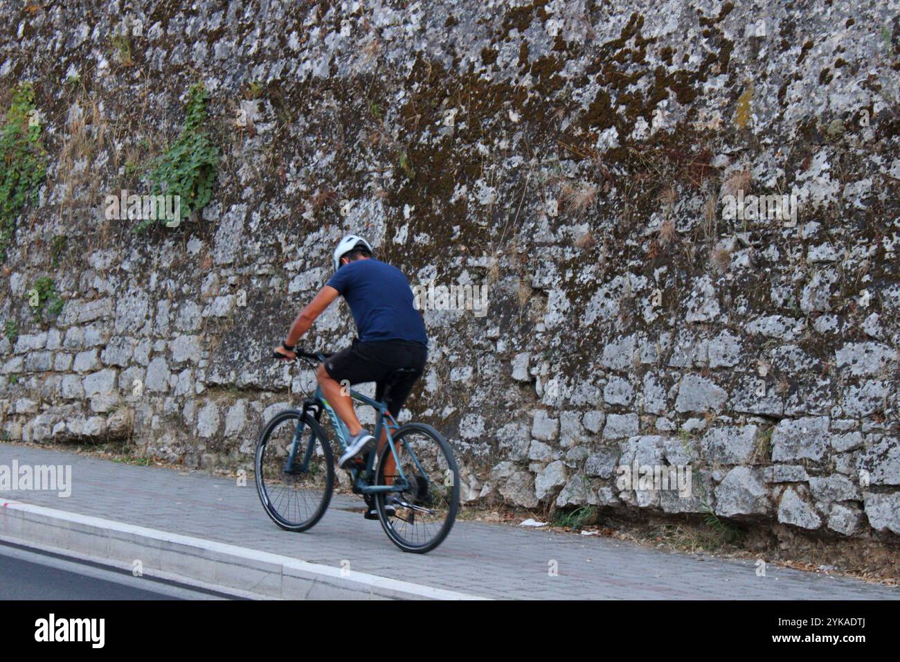 Man riding bicycle up steep hill in Corfu Town, Greece Stock Photo - Alamy