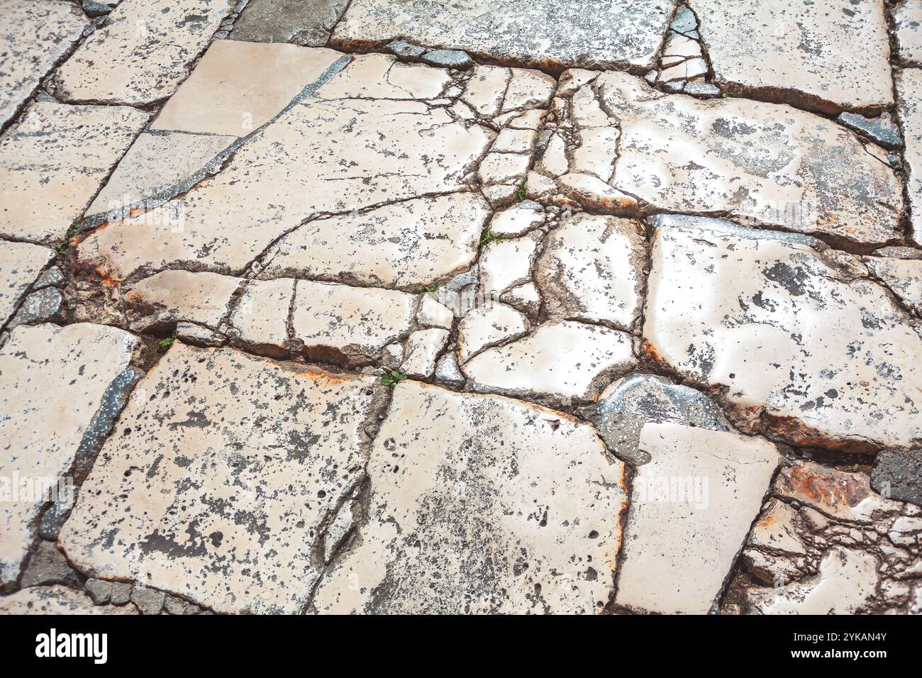 Section of an old cracked stone pavement. The stones are irregularly ...