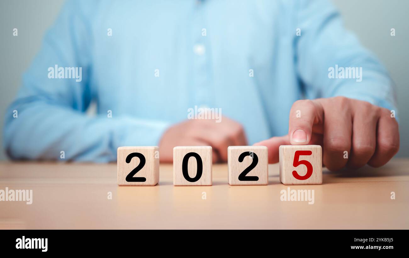 Businessman selected cube from 2025 on wooden table, Planning 2025 trends new year symbol ...