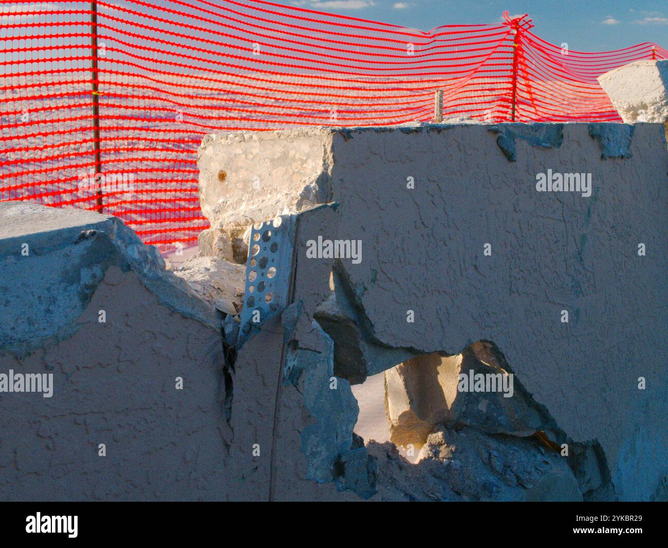 Over broken cracked concrete barrier by sidewalk through orange safety ...