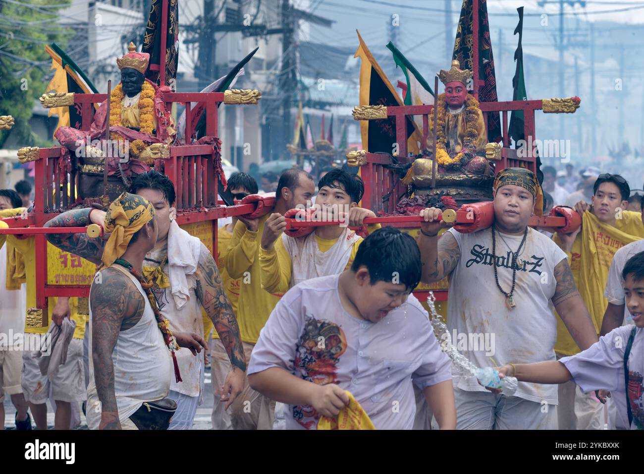 Young Thai men carrying palanquins with figures of Chinese gods during ...
